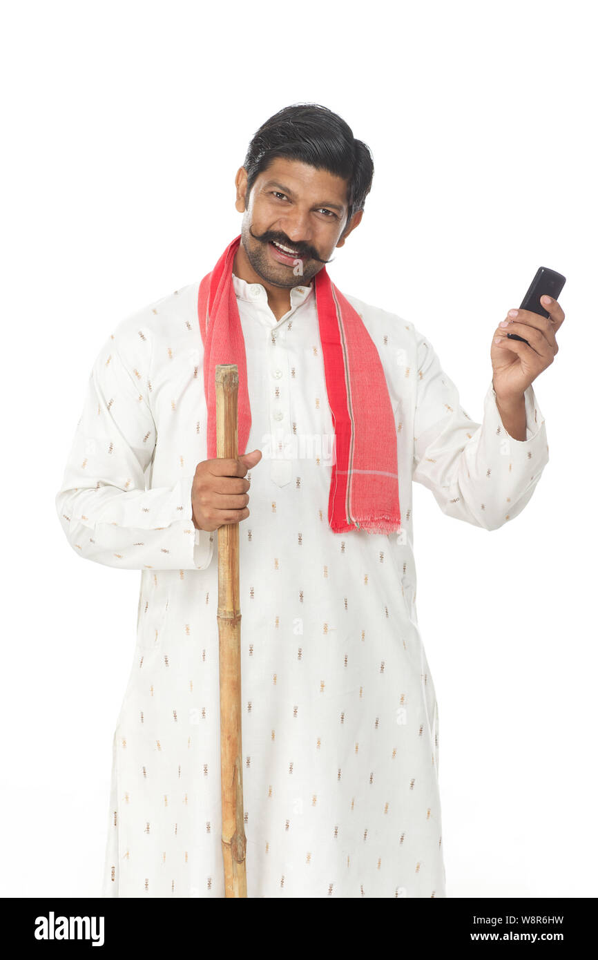 Rural man standing with cane and holding mobile phone Stock Photo - Alamy