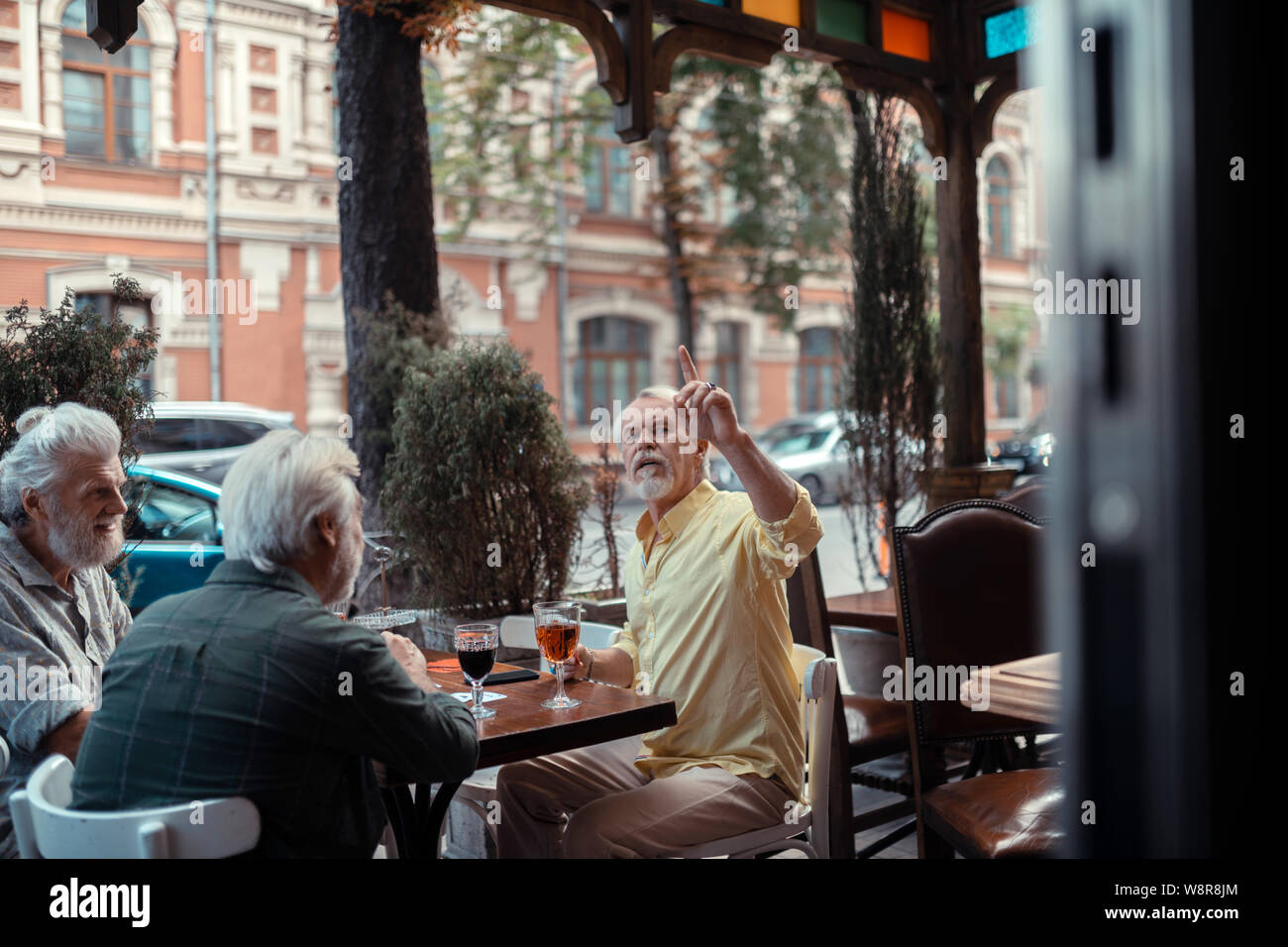 Man calling for waiter while sitting outside pub Stock Photo - Alamy