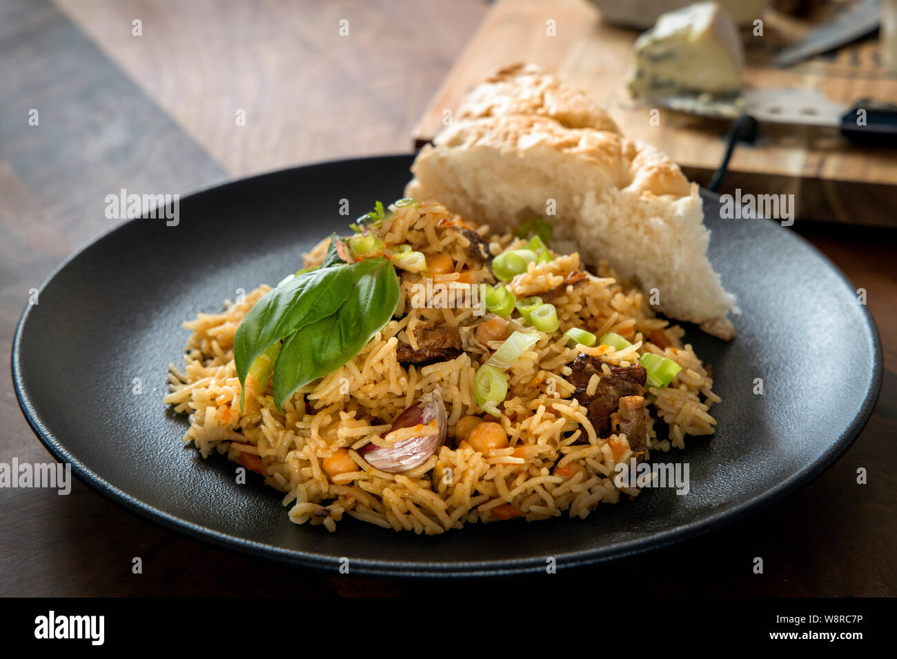 Traditional homemade Uzbek pilaf or plov on a wooden table concept of ...