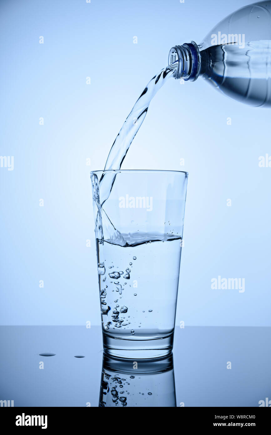 Vertical image in a tall glass cup pour clean water from a plastic ...