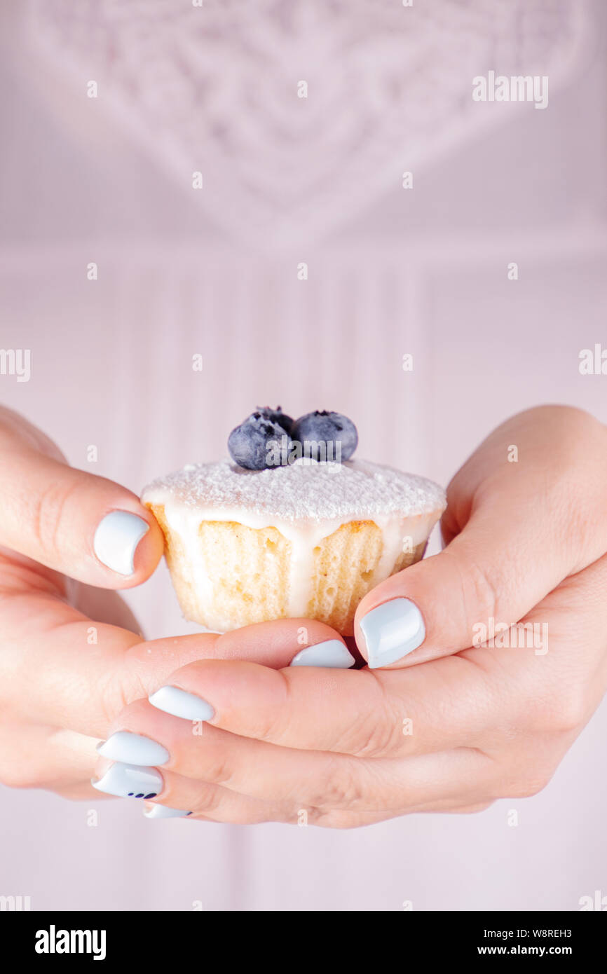 Iced sugar muffin with blueberry in woman hands Stock Photo - Alamy