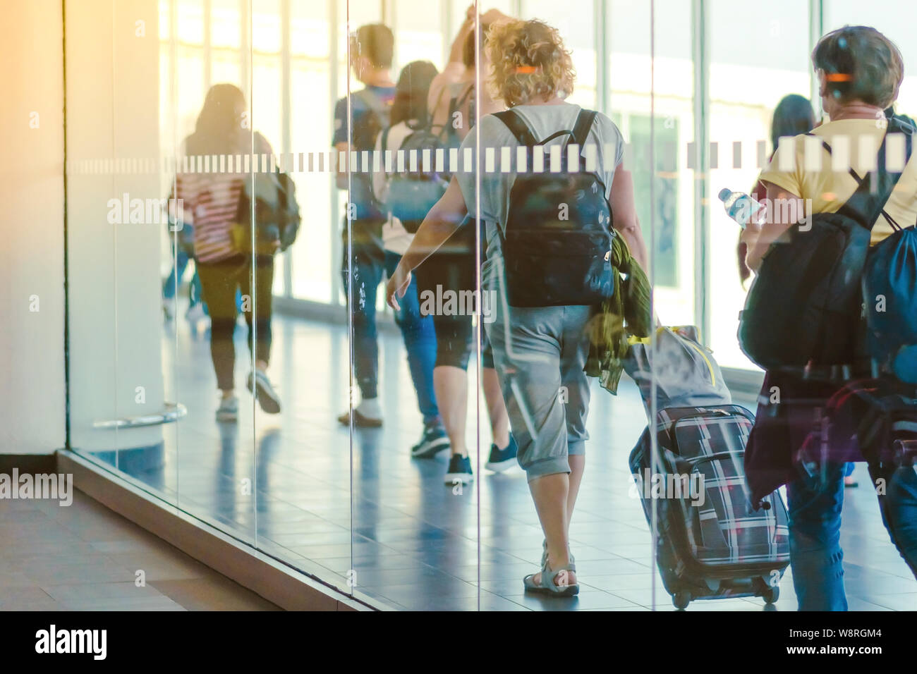 Back view of passengers and traveling luggage walking the airplane ...
