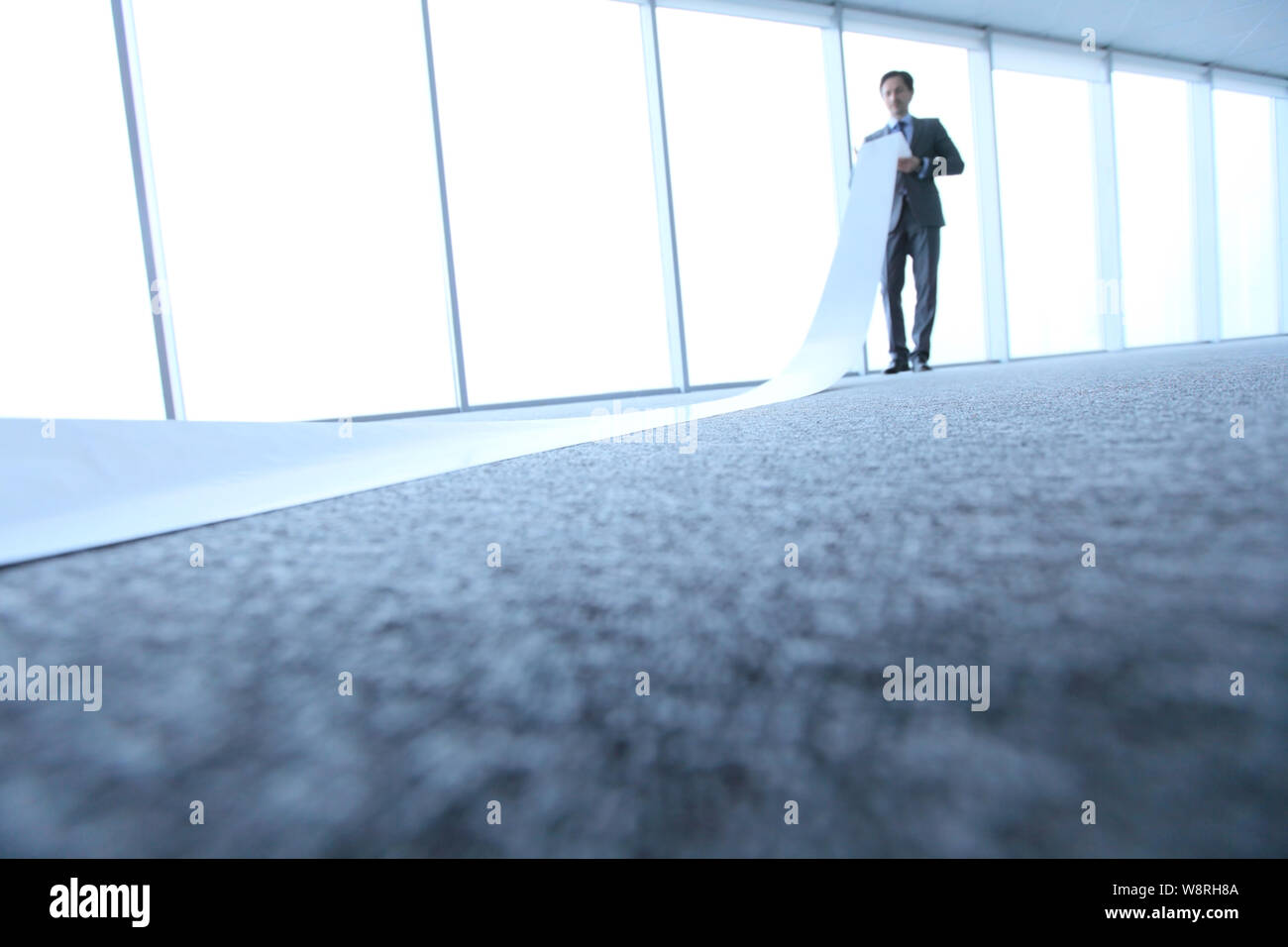 Office worker unrolling long sheet of paper Stock Photo - Alamy