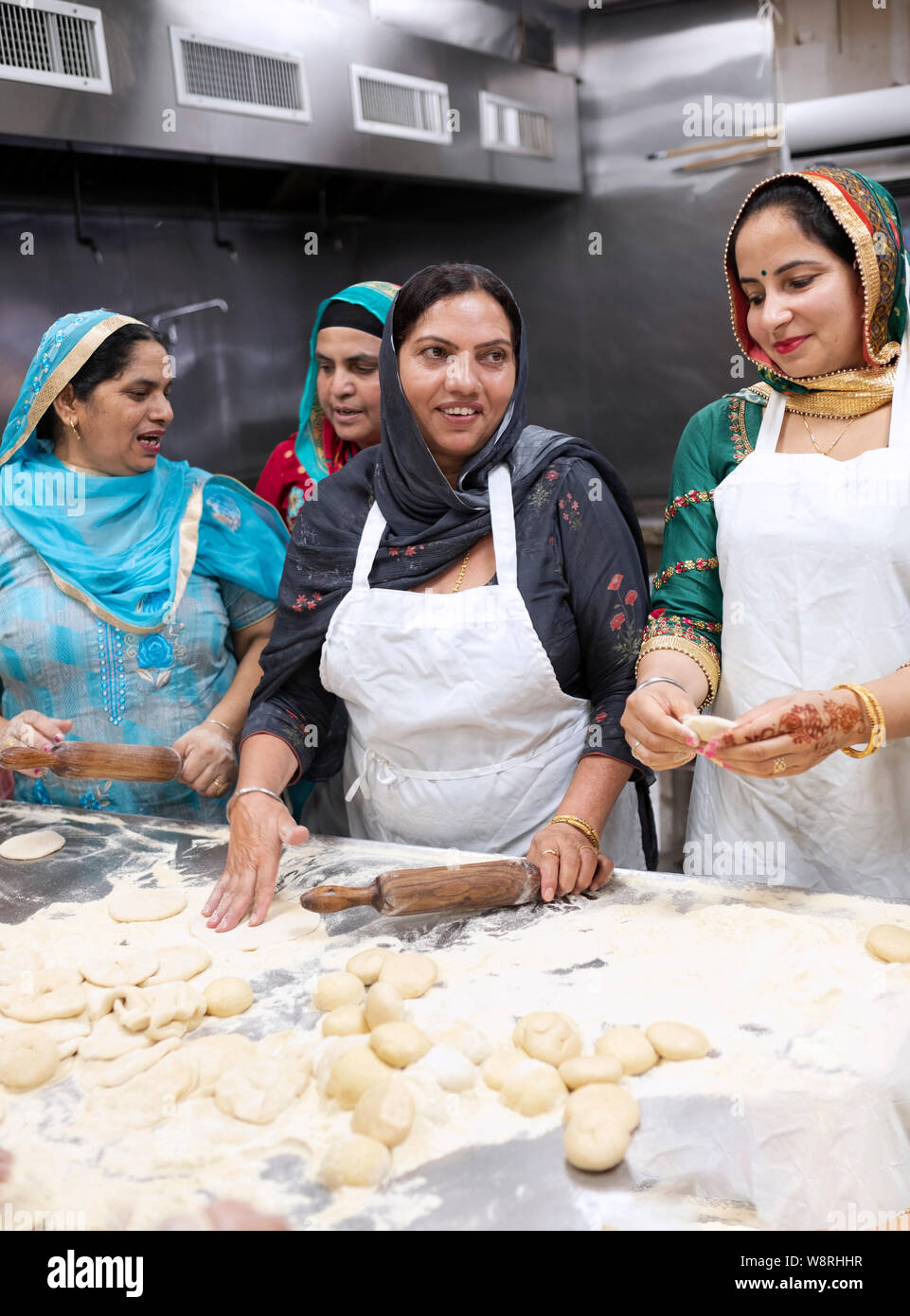 Volunteers of various ages prepare roti bread at a langar in a Sikh ...