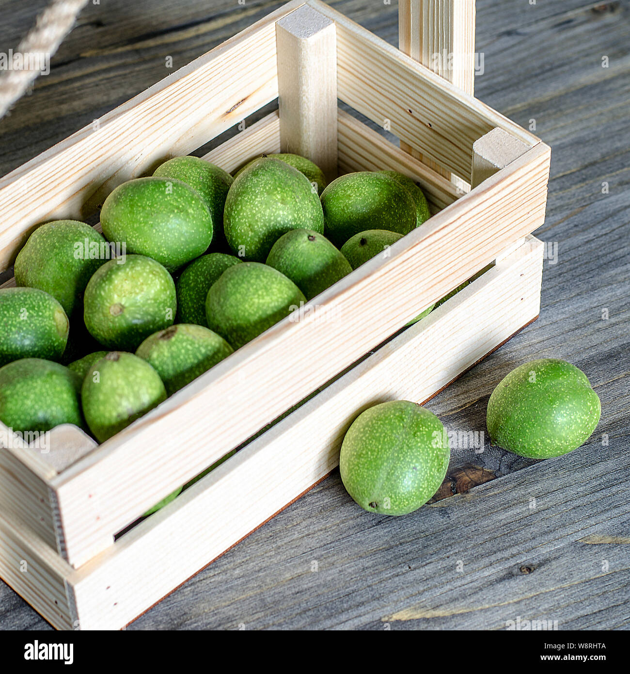 Young fruits of walnuts in a green shell in a wooden box Stock Photo ...