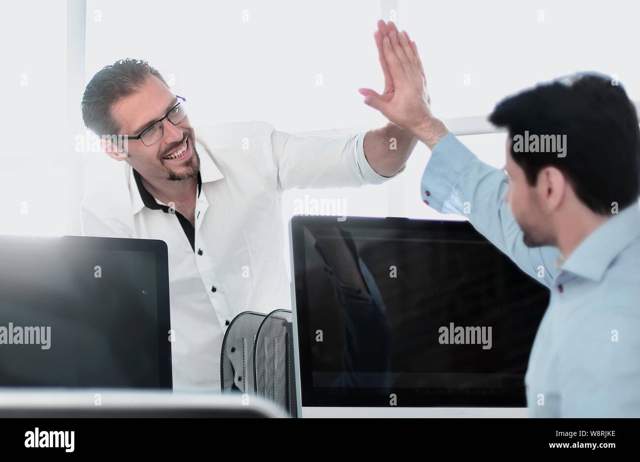 employees give each other a high five over the computer Desk Stock ...
