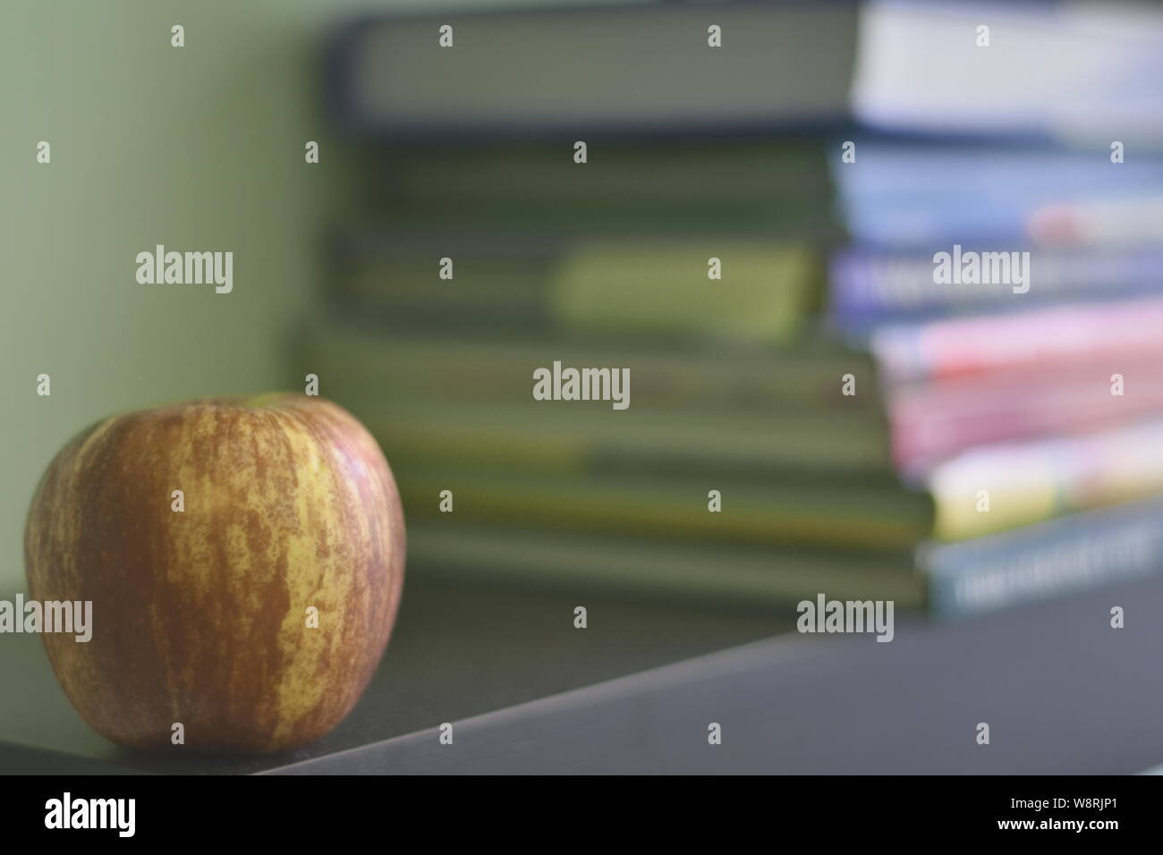 Back to school concept background. Red apple in front of blurred stack ...