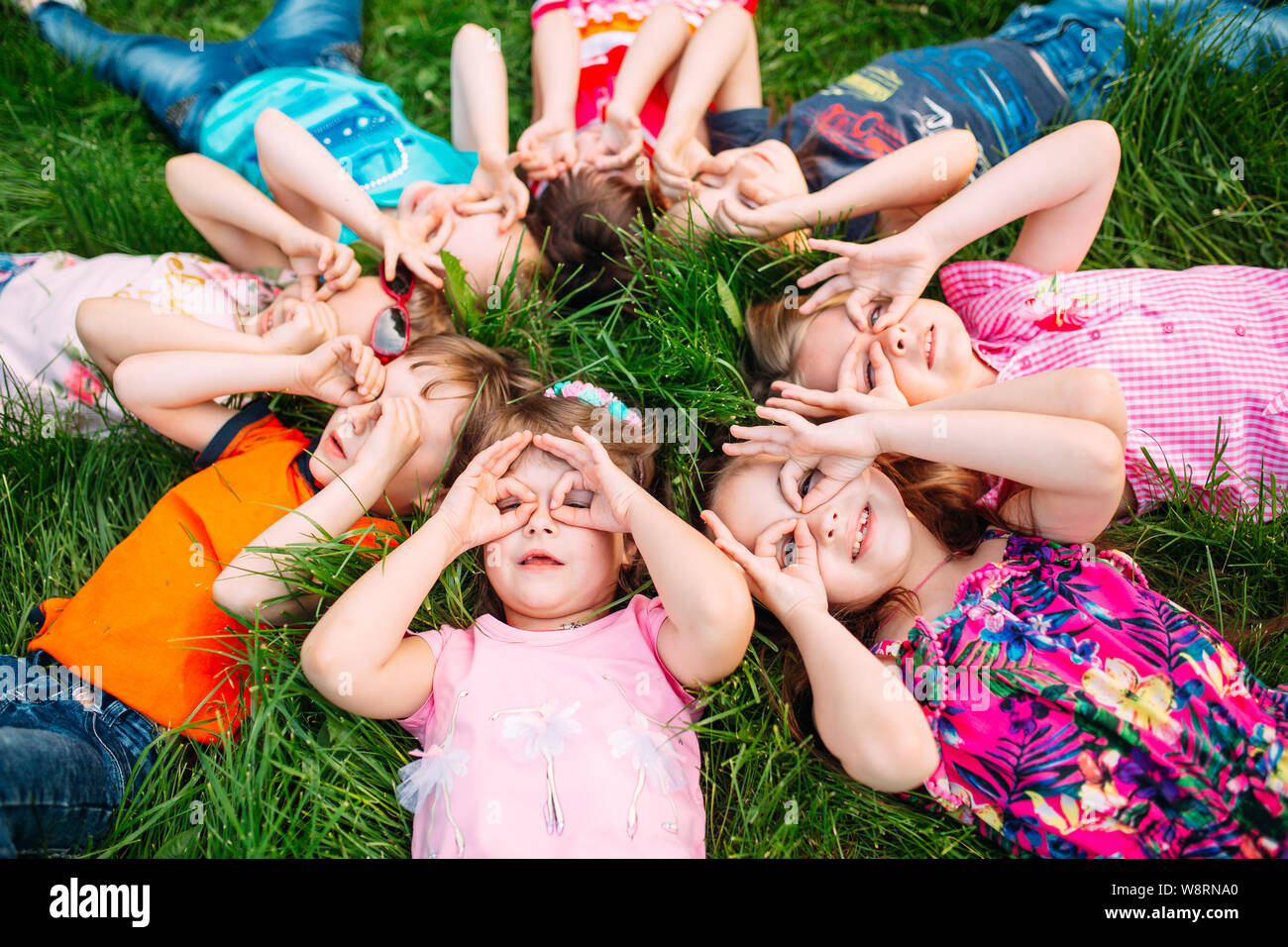 A group of children lying on the green grass in the Park. The ...