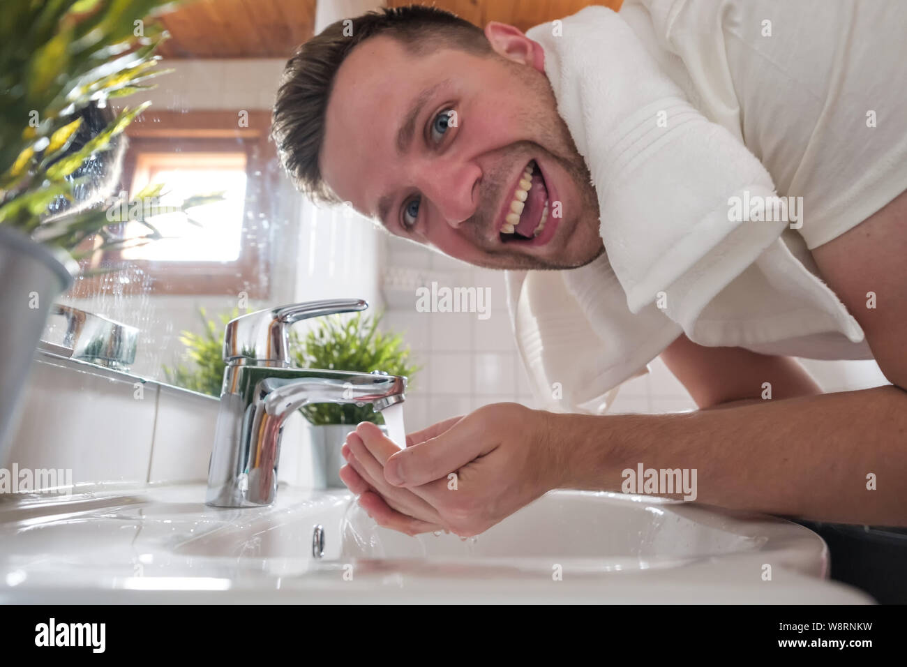 Caucasian man washing face in a wash basin in white washroom Stock ...