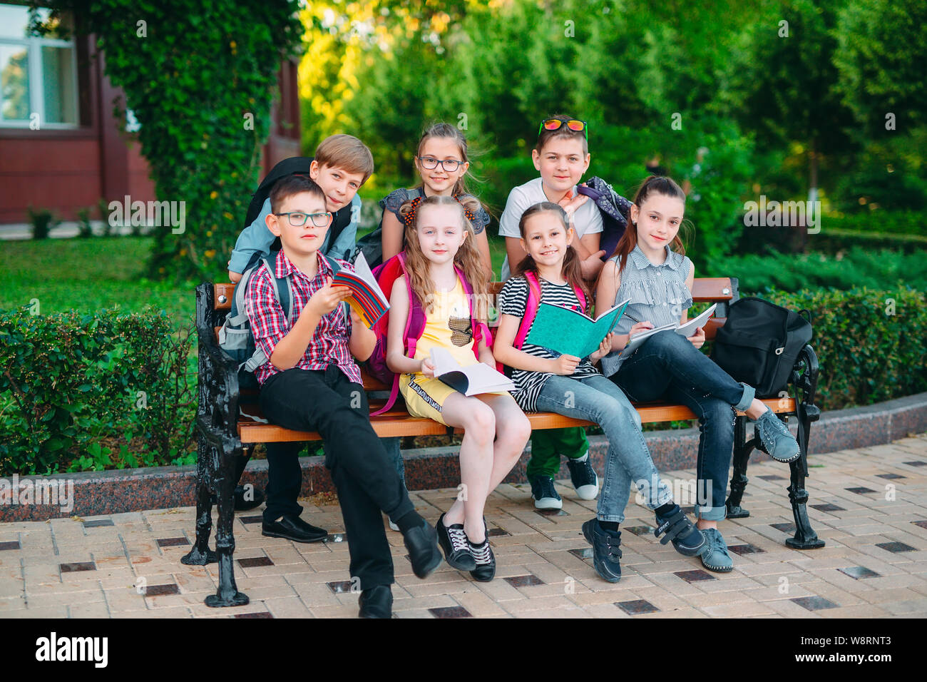Happy Schoolmates Portrait. Schoolmates seating with books in a wooden ...