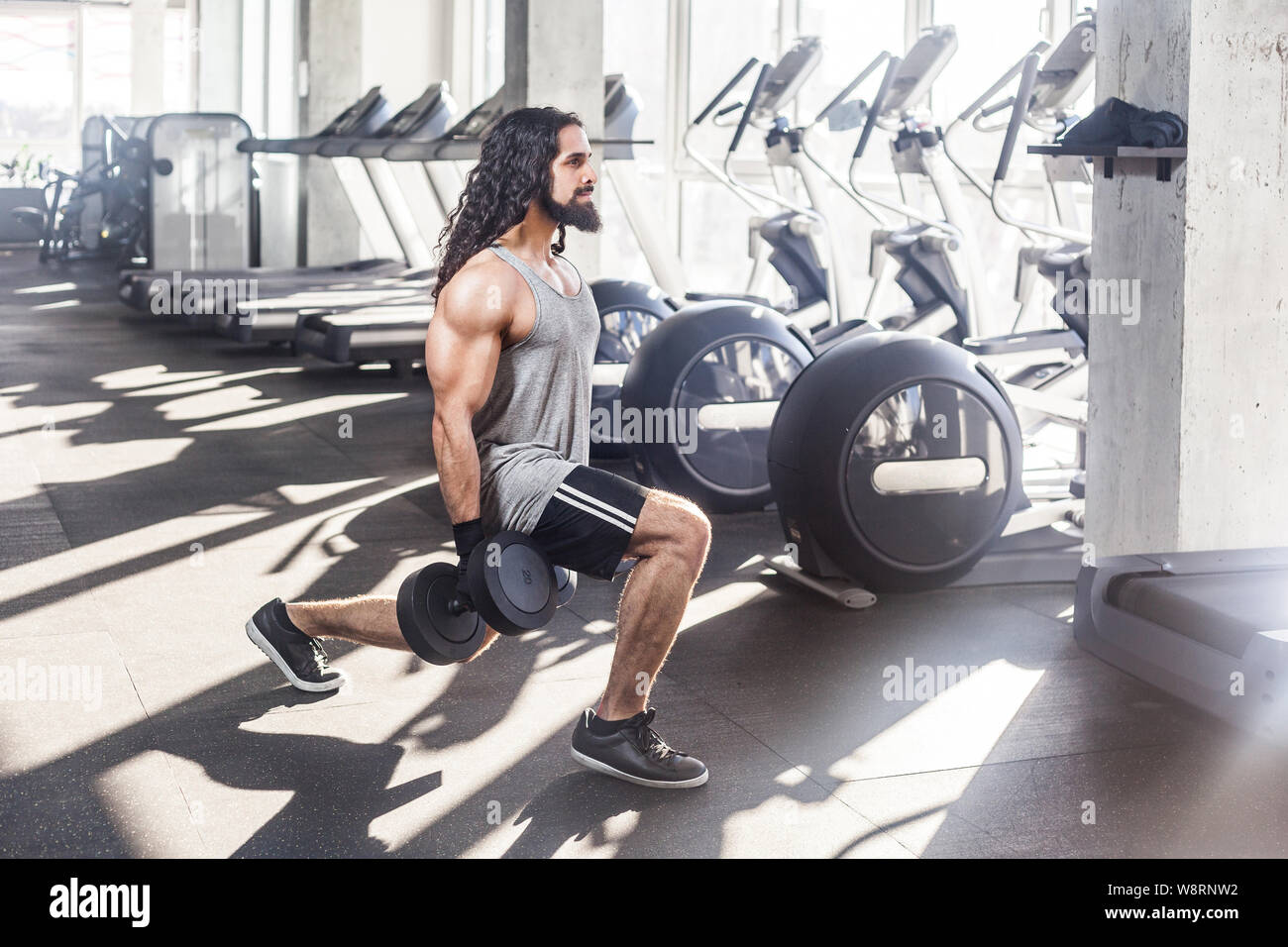 Side view of concentration young adult sportman athlete with long curly ...