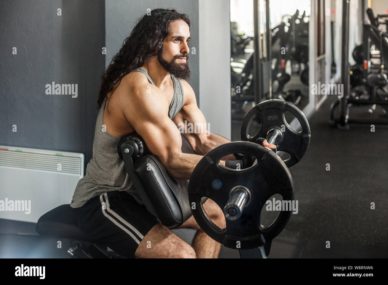 Side view portrait of young adult bodybuilder with long curly hair are ...