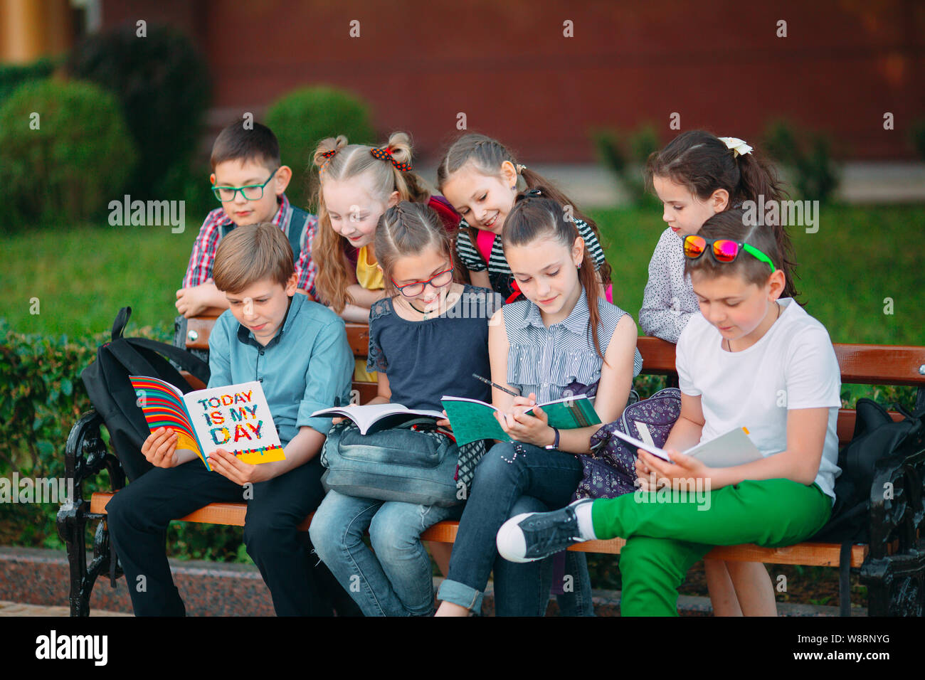 Happy Schoolmates Portrait. Schoolmates seating with books in a wooden ...