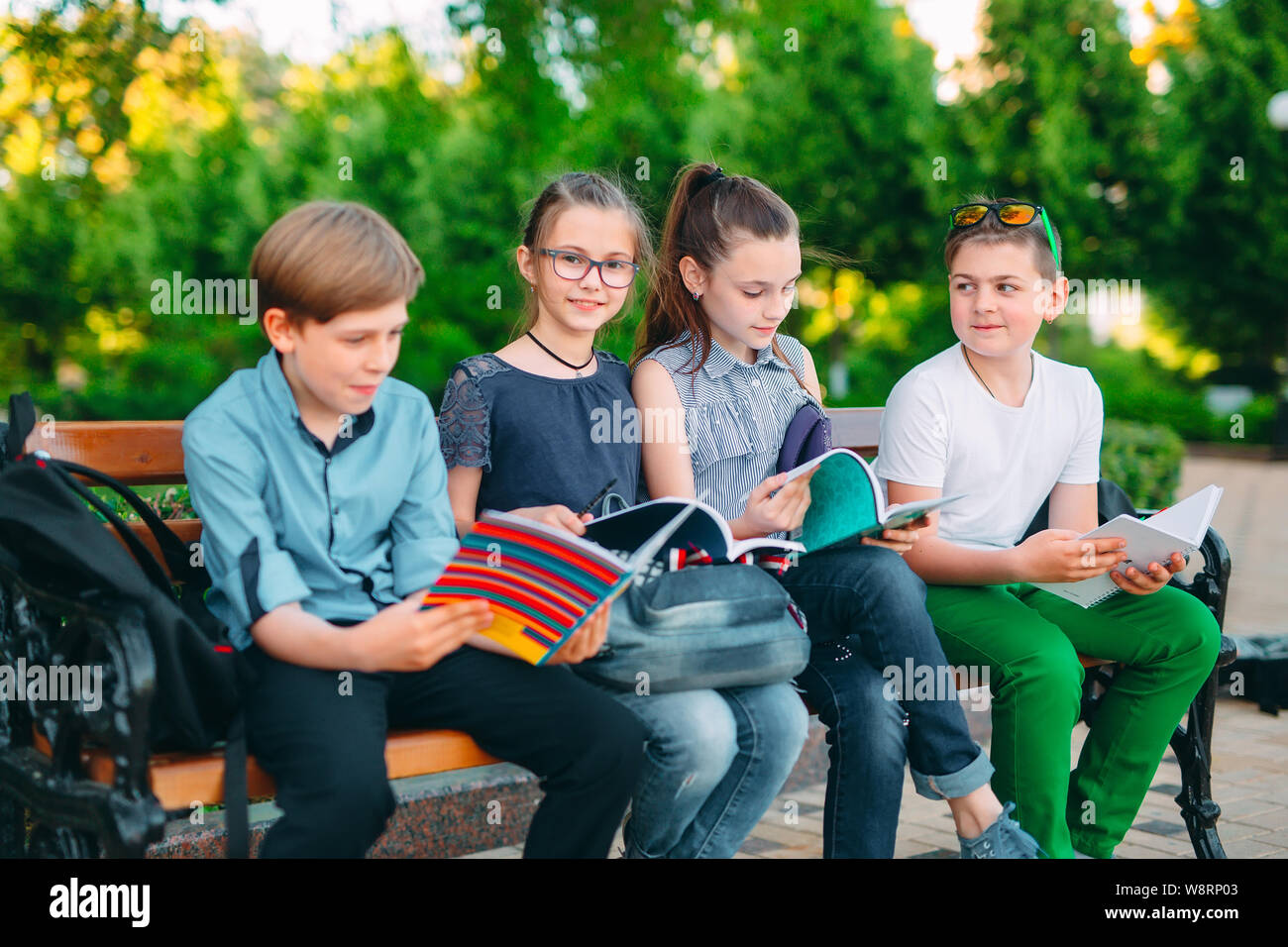 Happy Schoolmates Portrait. Schoolmates seating with books in a wooden ...