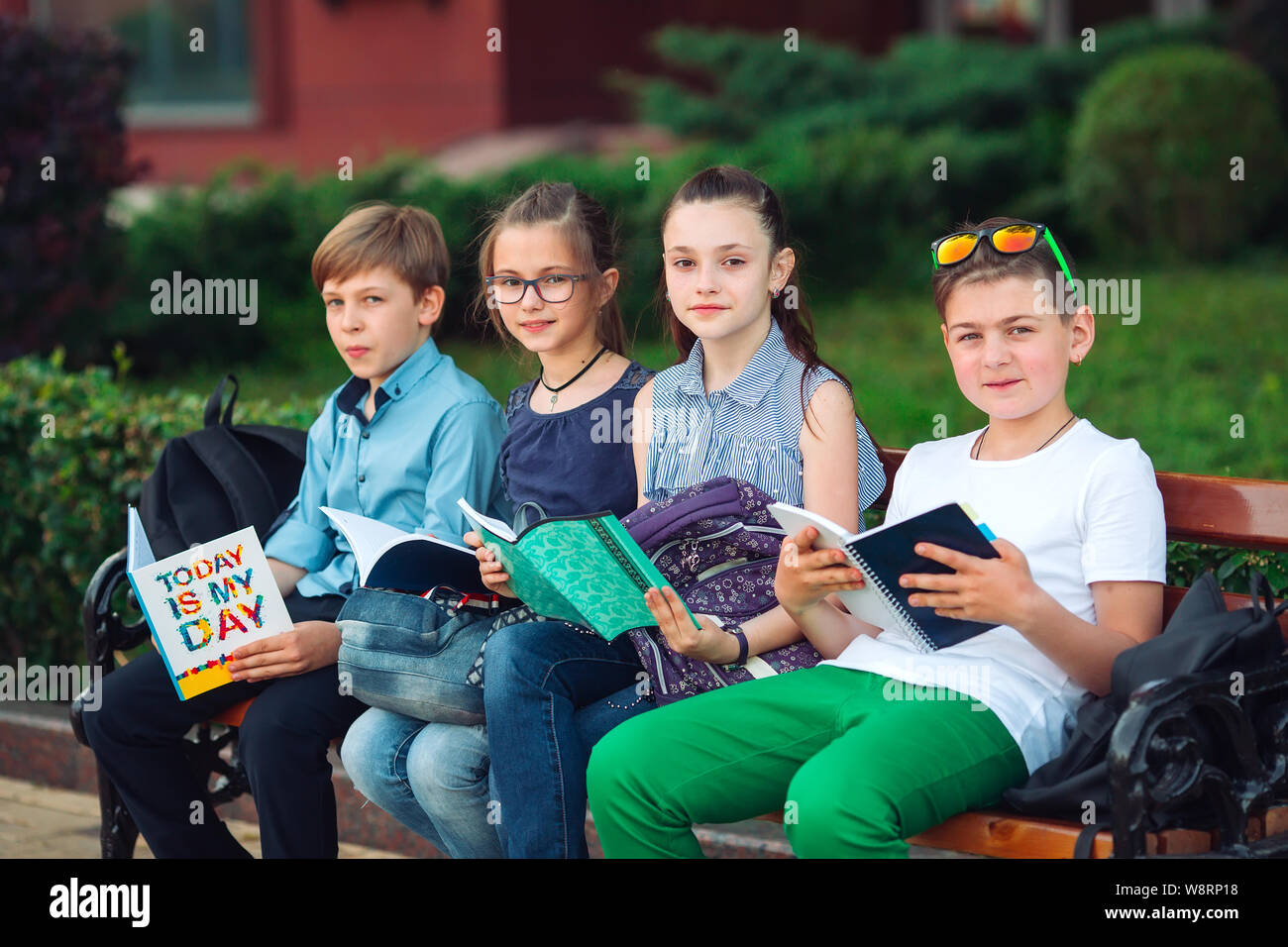 Happy Schoolmates Portrait. Schoolmates seating with books in a wooden ...