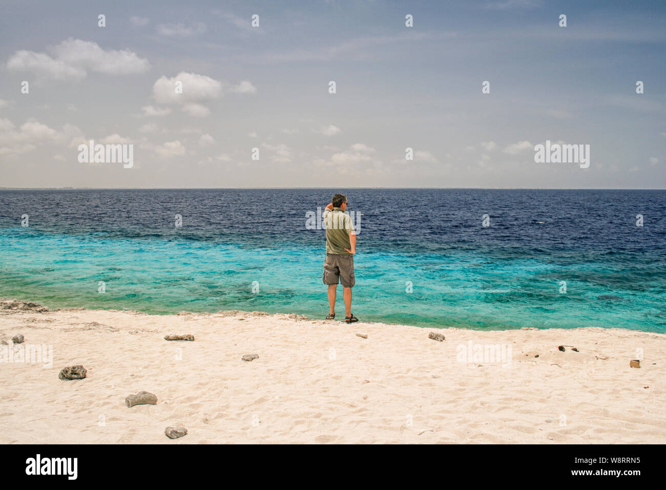 Man on caribbean beach staring at ocean Stock Photo - Alamy