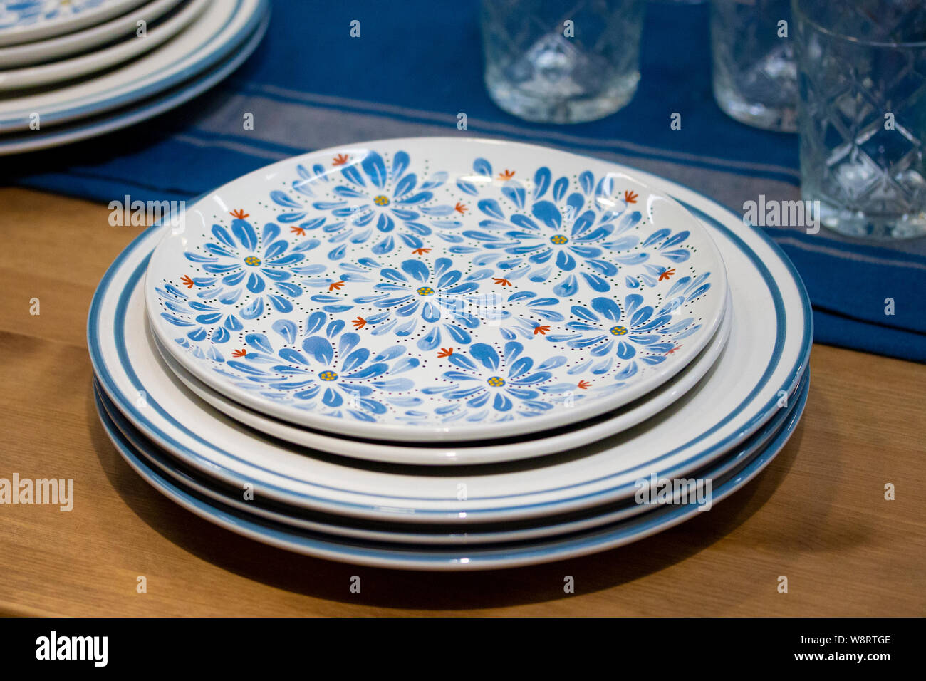 A stack of different blue plates with flowers with a strip on a wooden ...