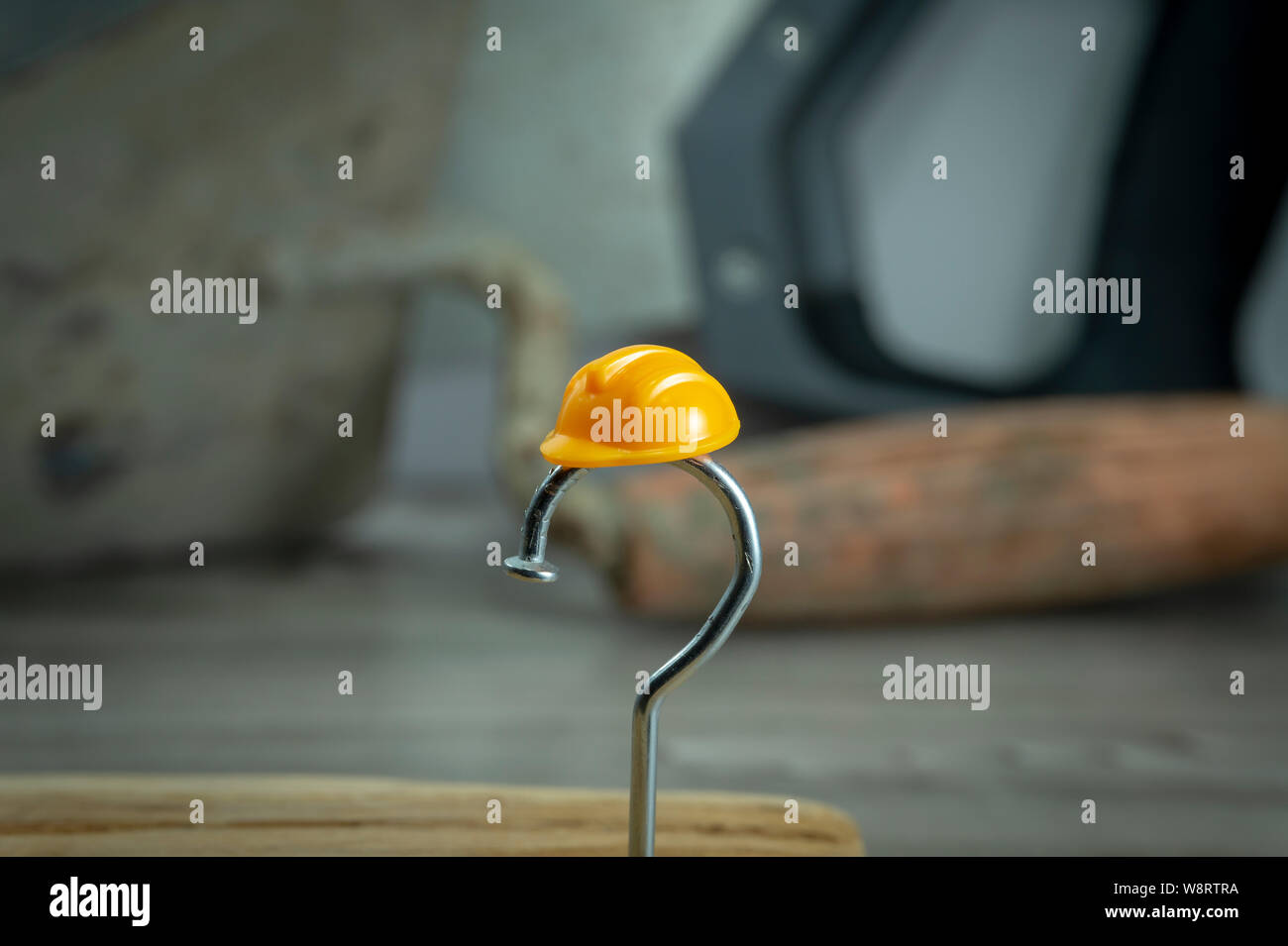 Construction nail shaped as question mark with yellow plastic workplace ...