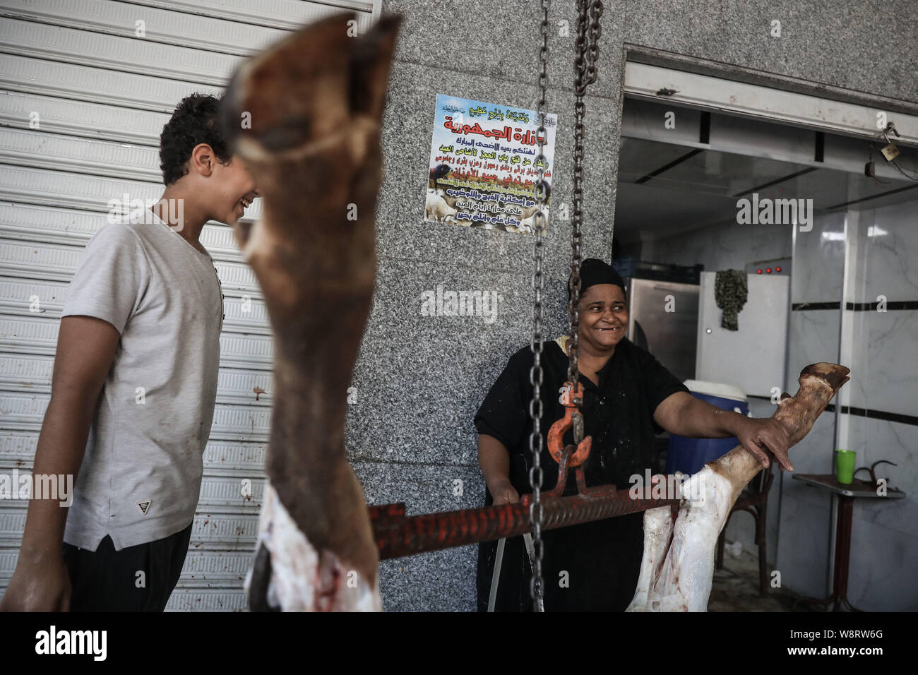 Cairo, Egypt. 11th Aug, 2019. A woman stands behind a cow carcass after ...