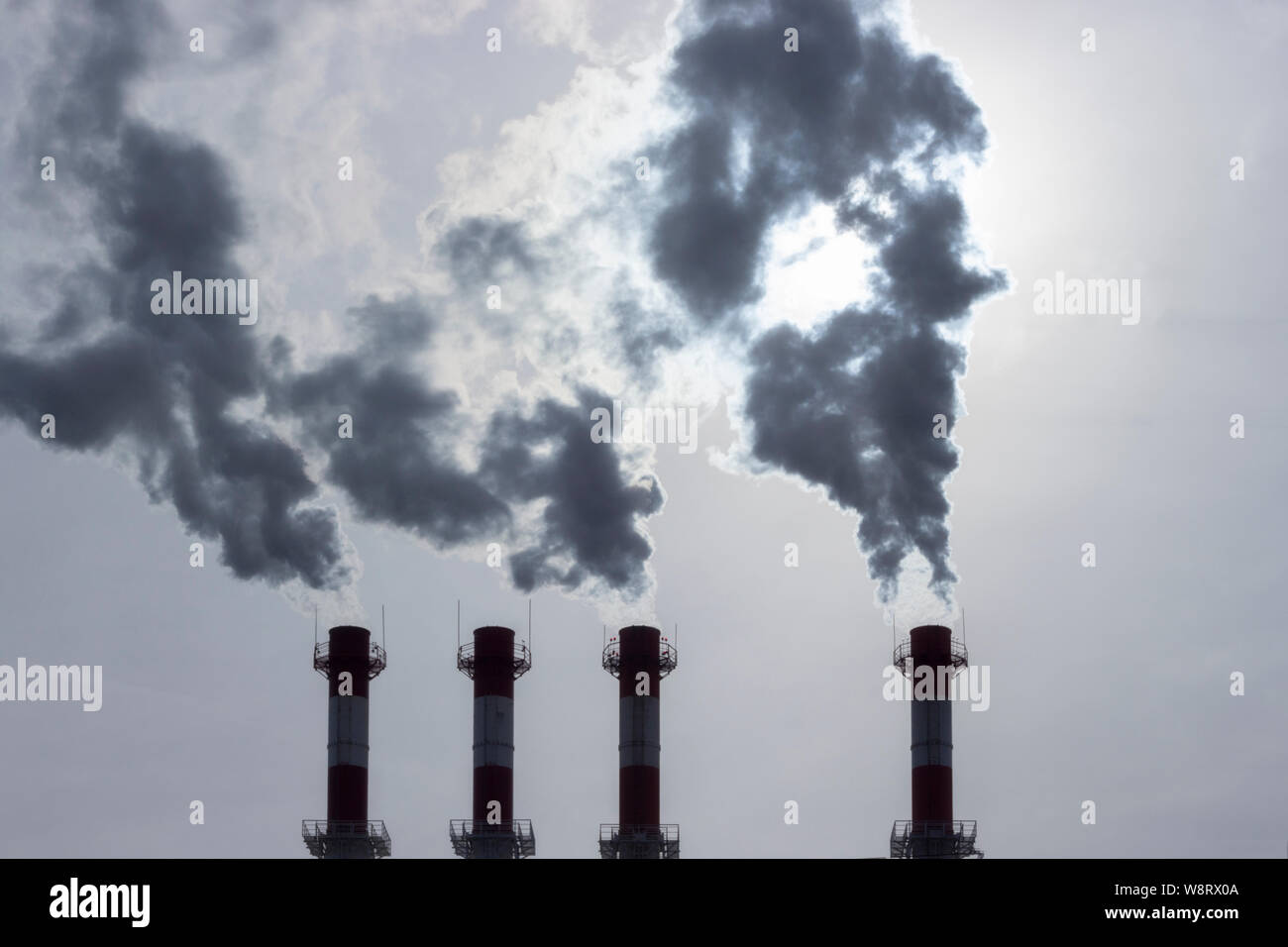 Silhouettes of pipes emitting dark steam into the atmosphere. Steam ...