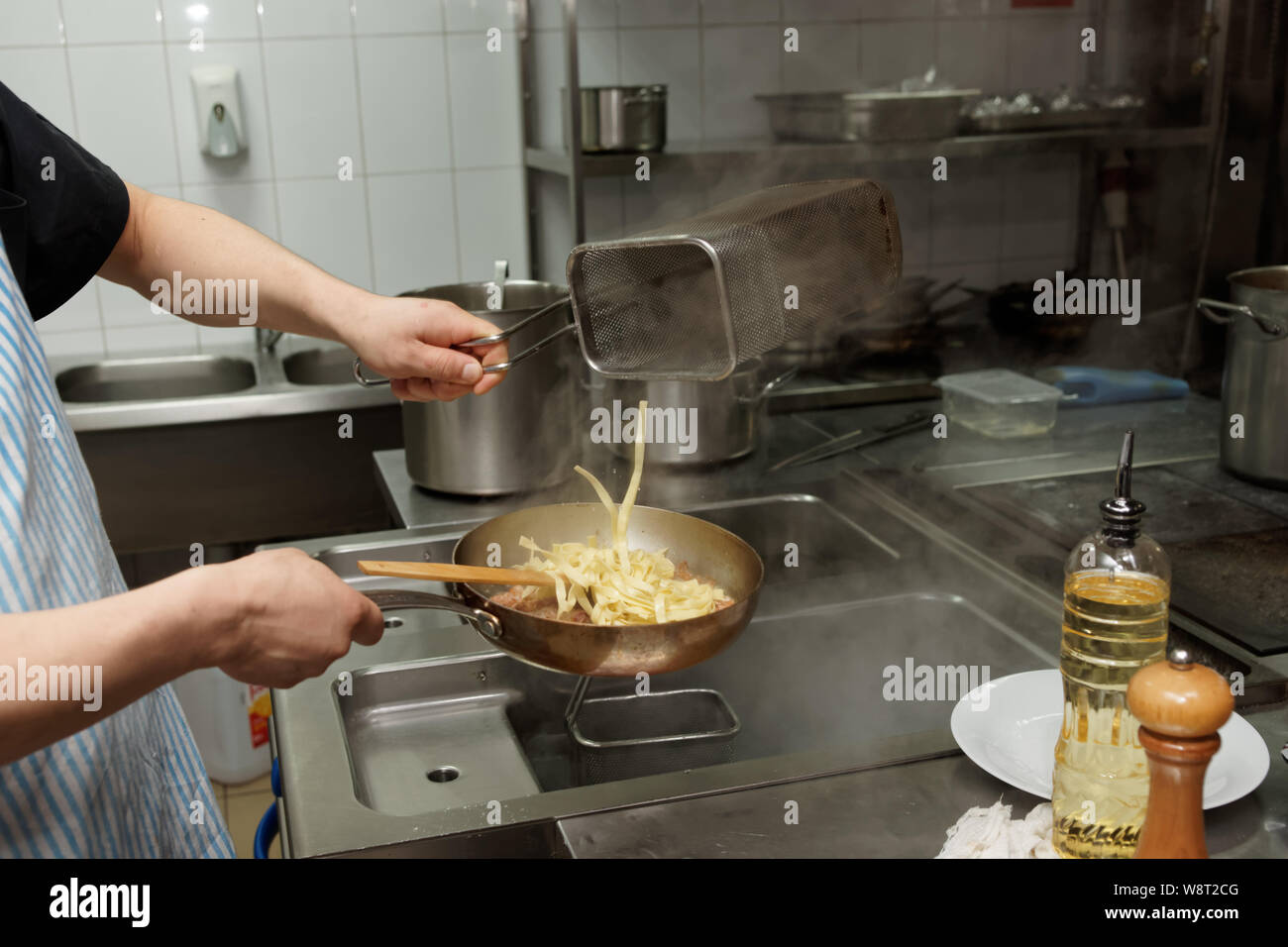 Chef is cooking pasta in professional kitchen Stock Photo - Alamy