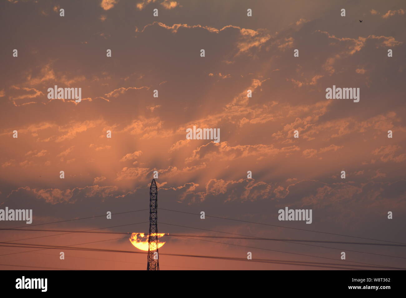 Morning sun behind electricity pole with dramatic clouds at sky, clean ...