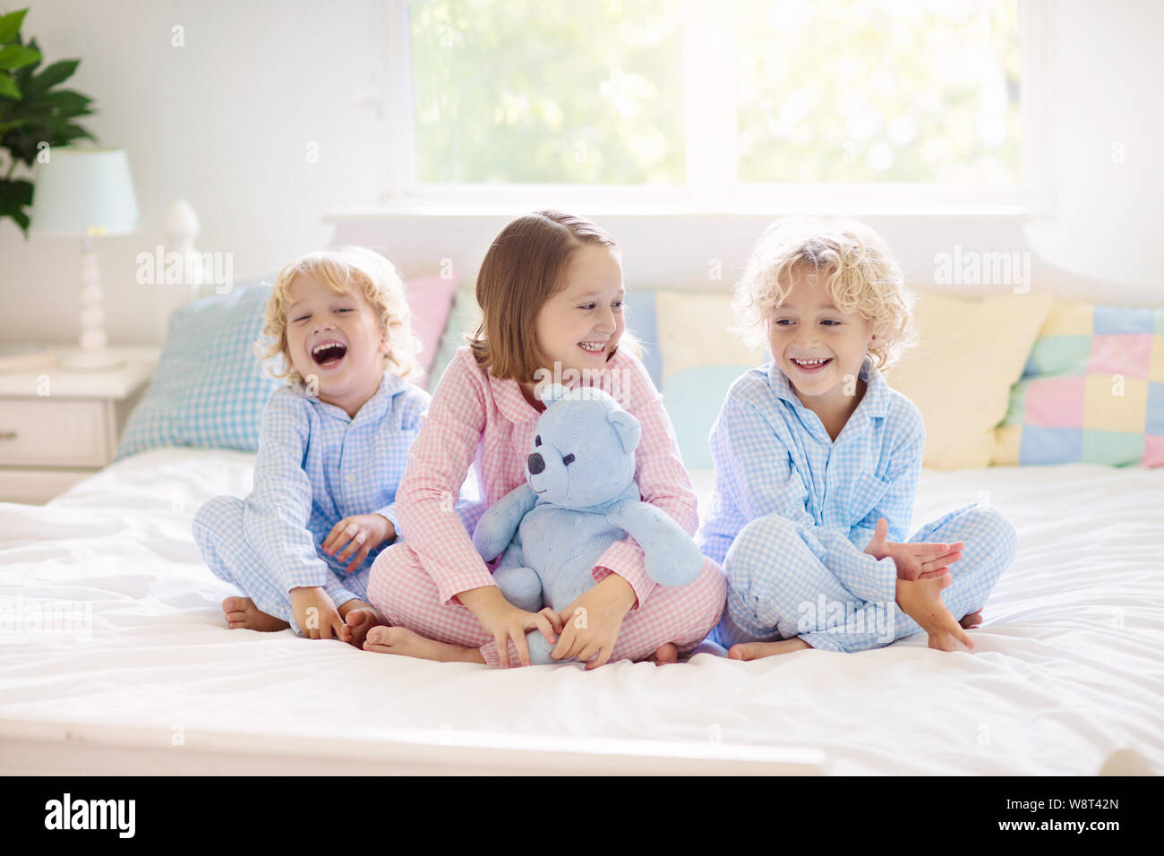 Kids play in bed. Children at home in white sunny bedroom. Brother and ...