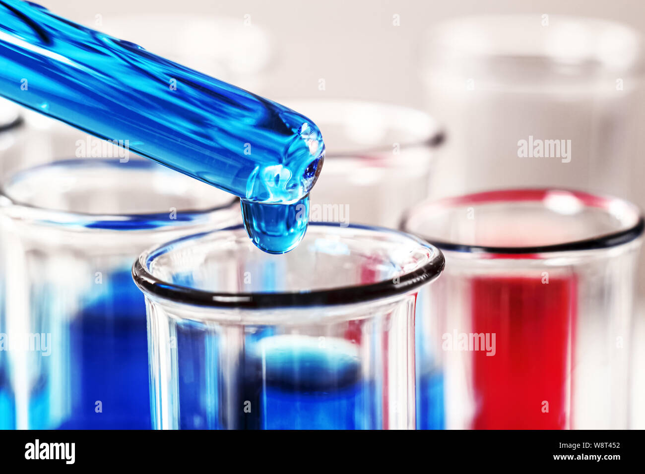 Close-up of a drop of liquid on a pipette falling into a test tube ...