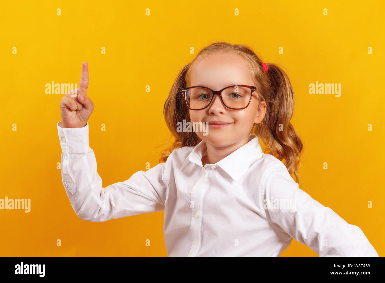 A child with glasses shows his index finger up. Portrait of a little ...