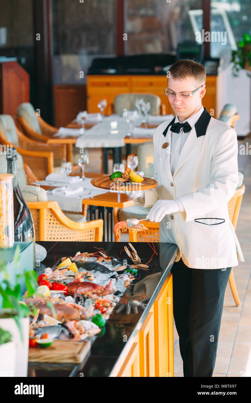 The waiter shifts the seafood on a tray in the restaurant Stock Photo ...