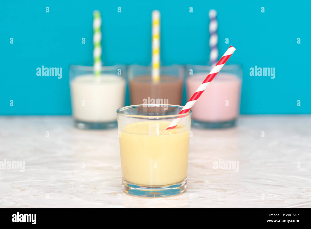 Banana milkshake with a retro paper straw in front of a row of fresh ...