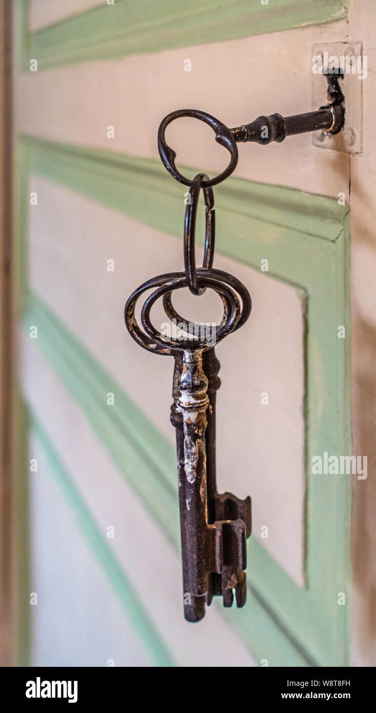 Old keys hanging out of keyhole in old French door Stock Photo - Alamy