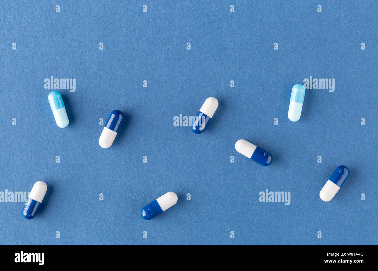 Various white-blue medication capsules. Blue background with text space ...