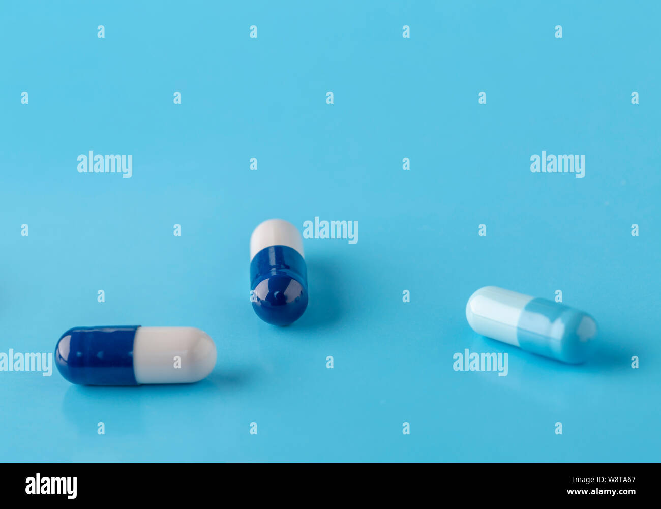 Various white-blue medication capsules. Blue background with text space ...
