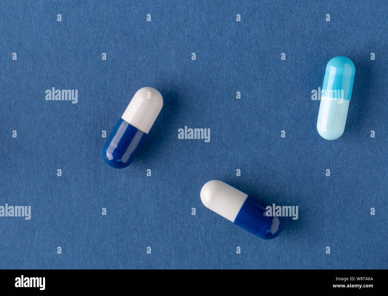 Various white-blue medication capsules. Blue background with text space ...