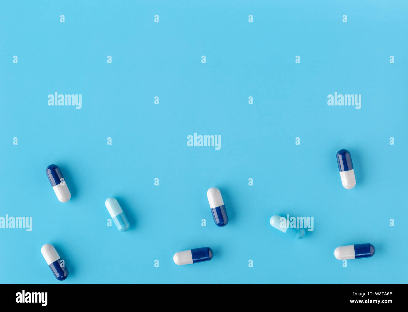 Various white-blue medication capsules. Blue background with text space ...