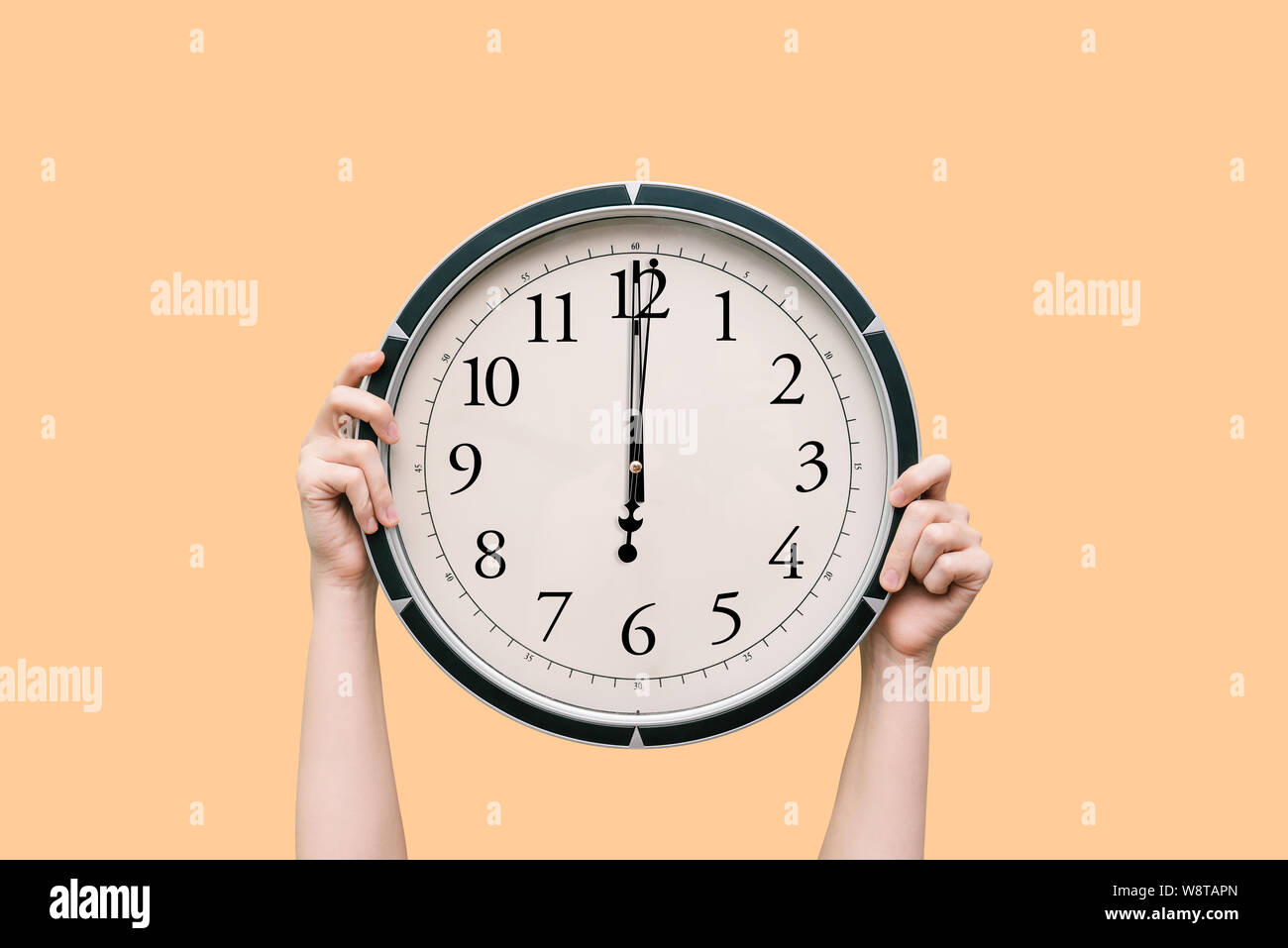 Round clock in the hands of a girl. Large round dial. The clock shows ...