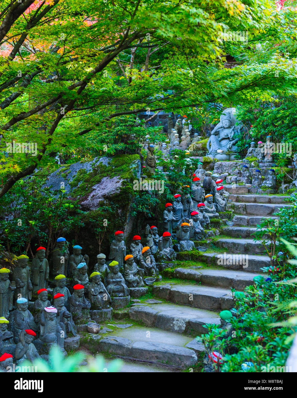 Many tiny buddhistic monk stone statues with colourful caps on their ...