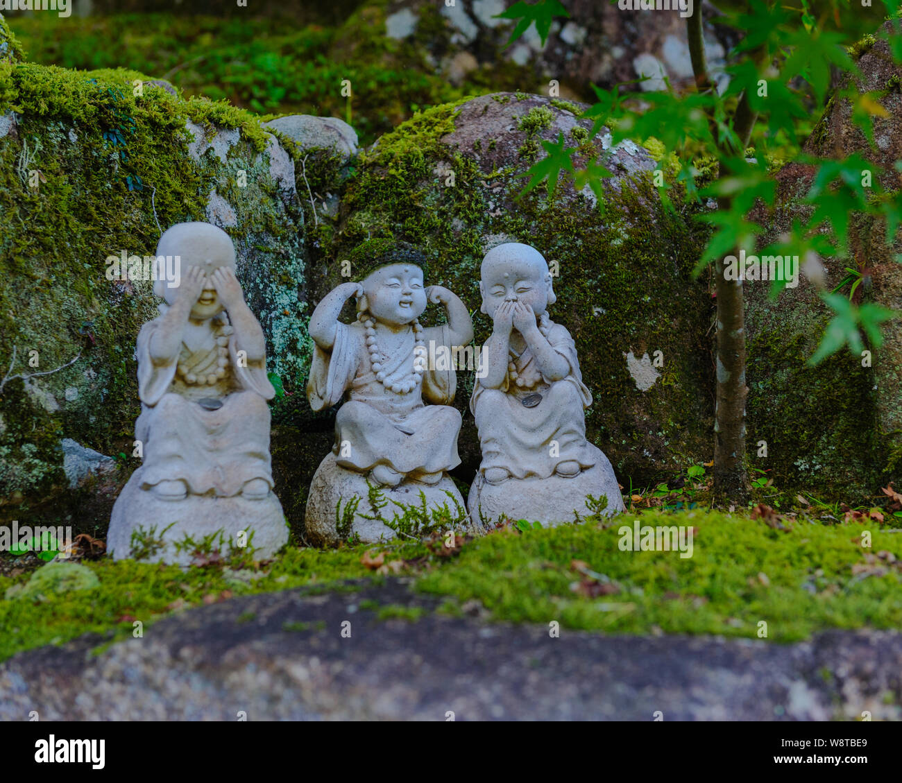 Group of three stone statues of buddhistic monks holding their eyes ...