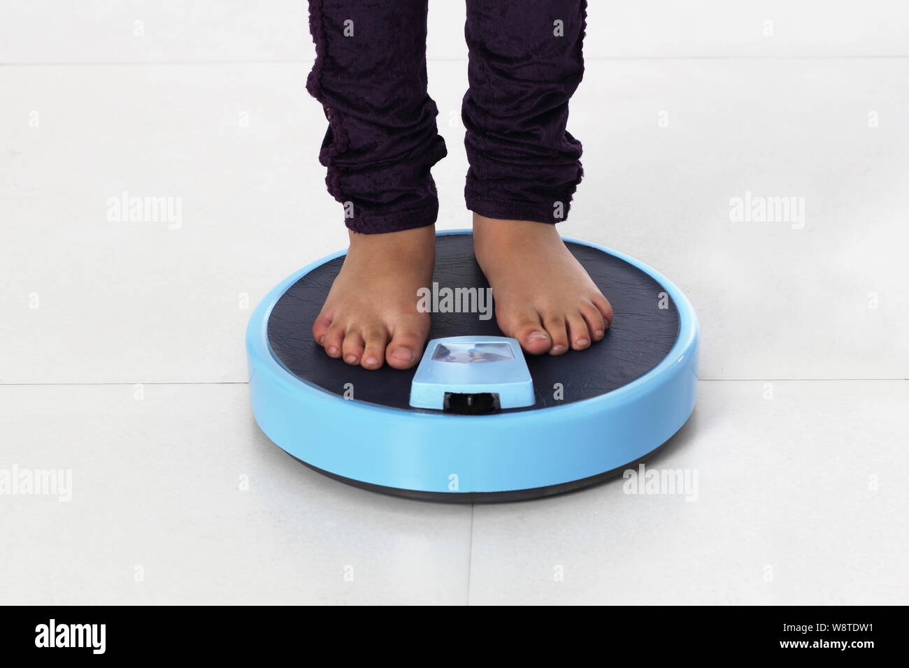 Child weighing itself on a bathroom scale Stock Photo - Alamy