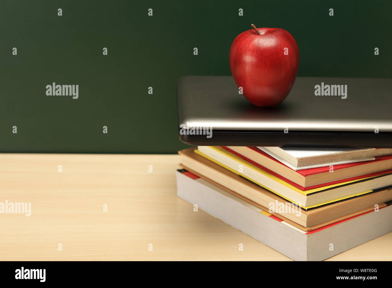 Apple and a laptop on a stack of books Stock Photo - Alamy