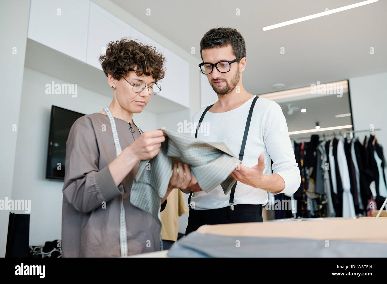 Young man and woman choosing textile for new fashion collection in ...