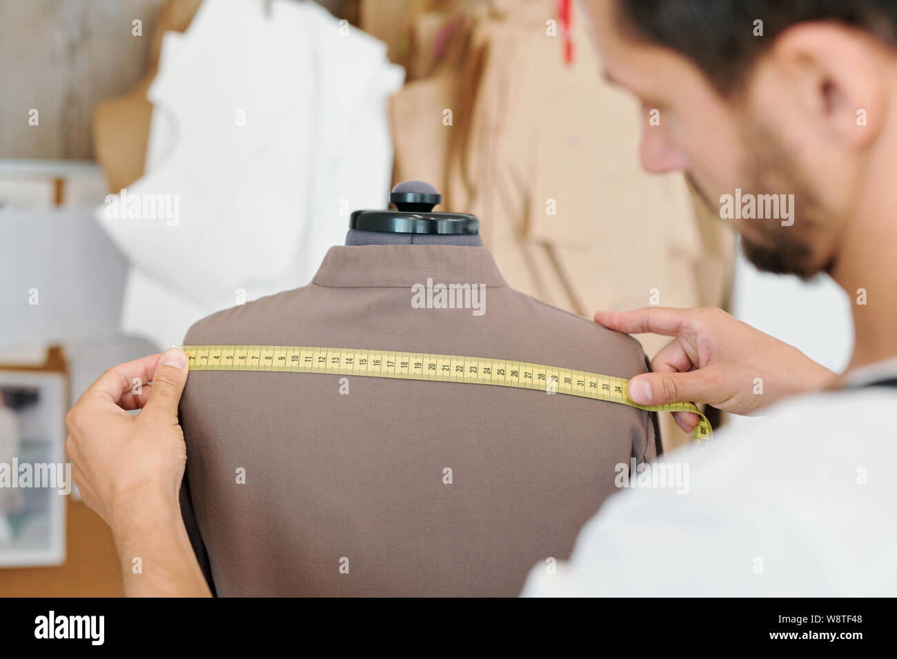 Male tailor measuring back of new jacket on dummy during work Stock ...