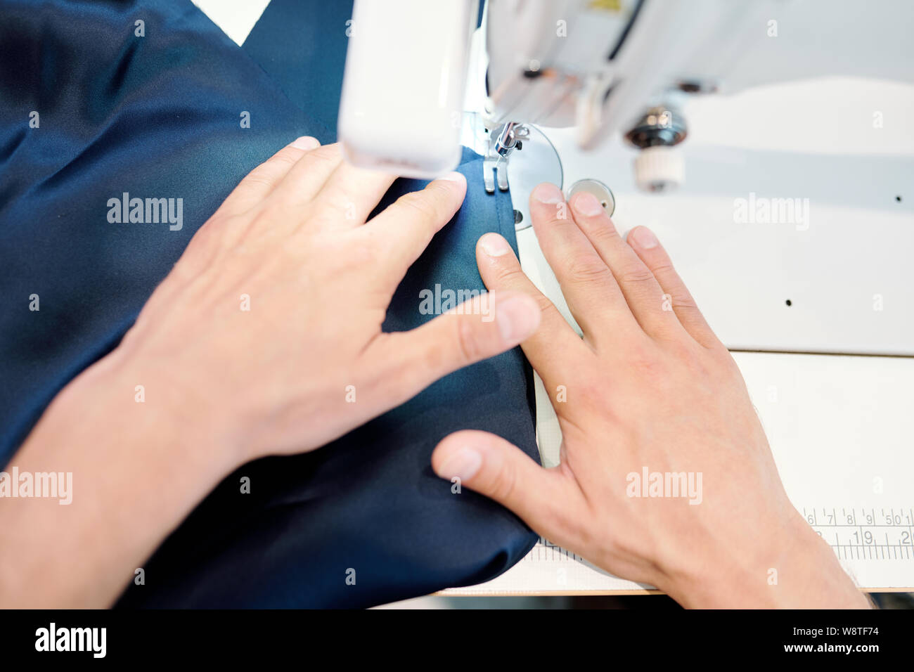 Human hands holding dark blue fabric while sewing by machine Stock ...