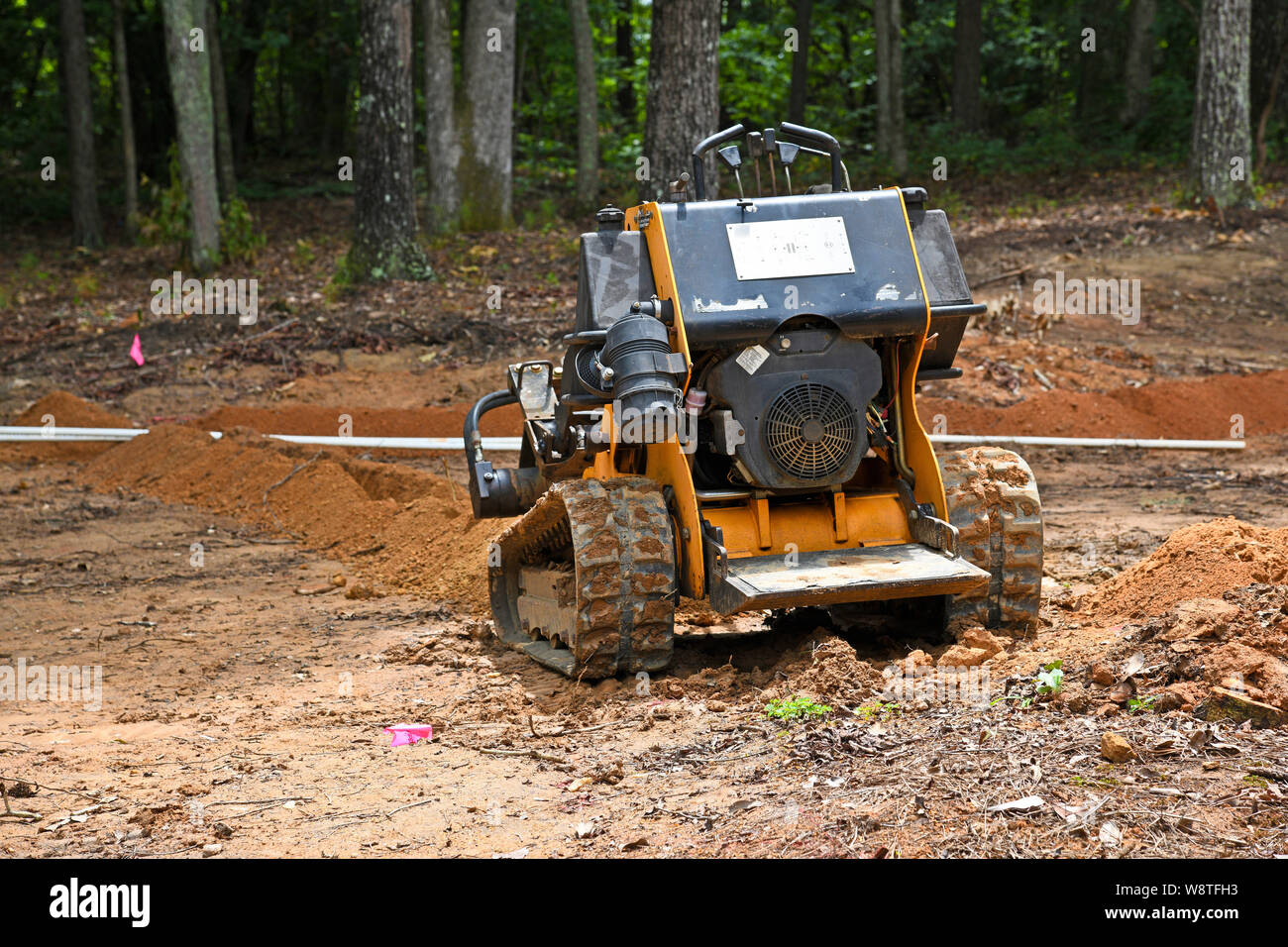 A commercial ditch digging machine cutting a trench in yard to install ...