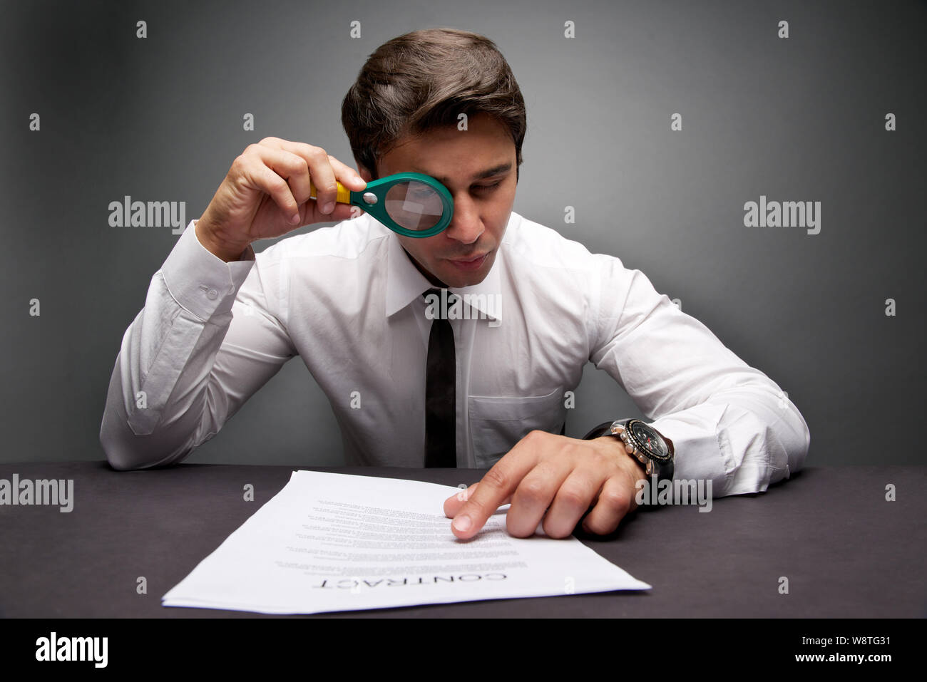 Businessman looking a document through magnifying glass Stock Photo - Alamy