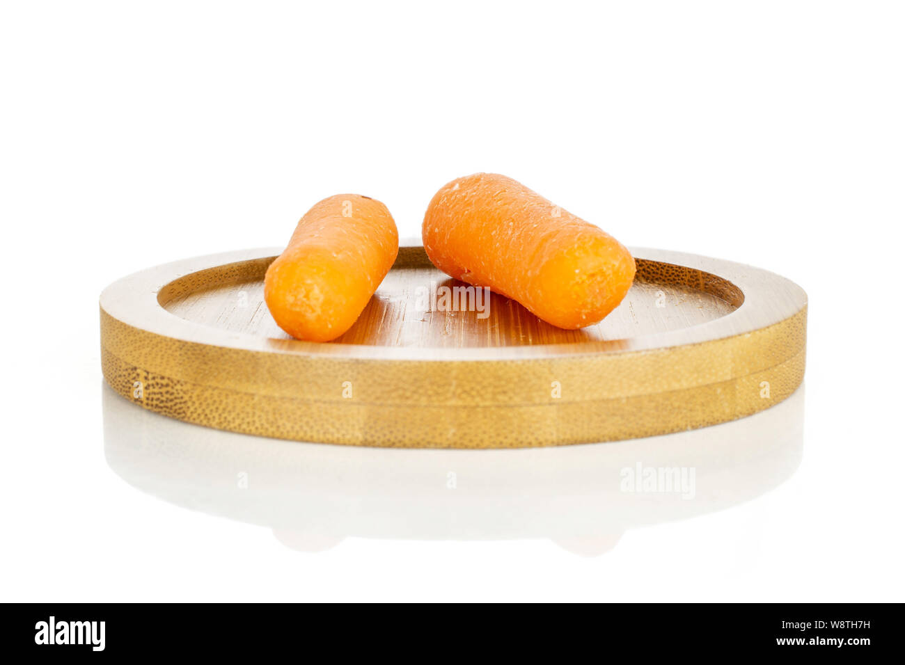 Group of two whole stale orange stale baby carrot baby on bamboo plate ...