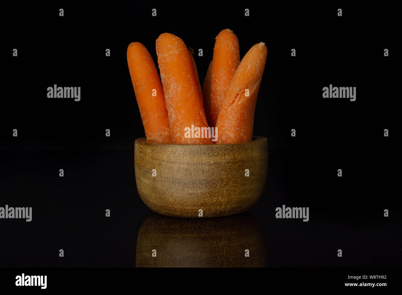 Group of four whole stale orange stale baby carrot baby in wooden cup ...