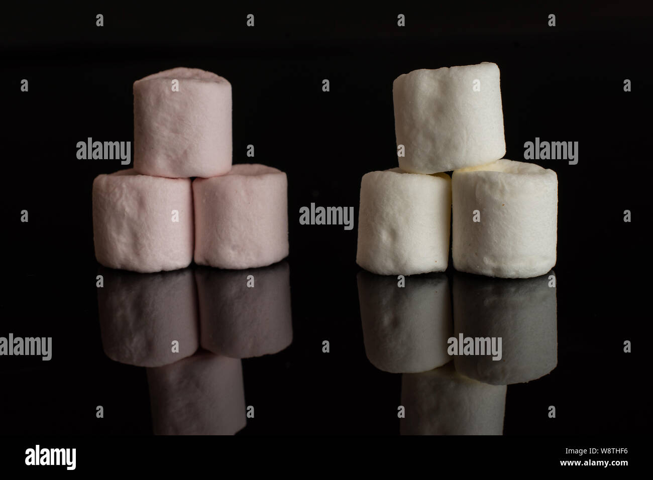 Group of six whole sweet fluffy marshmallow isolated on black glass ...