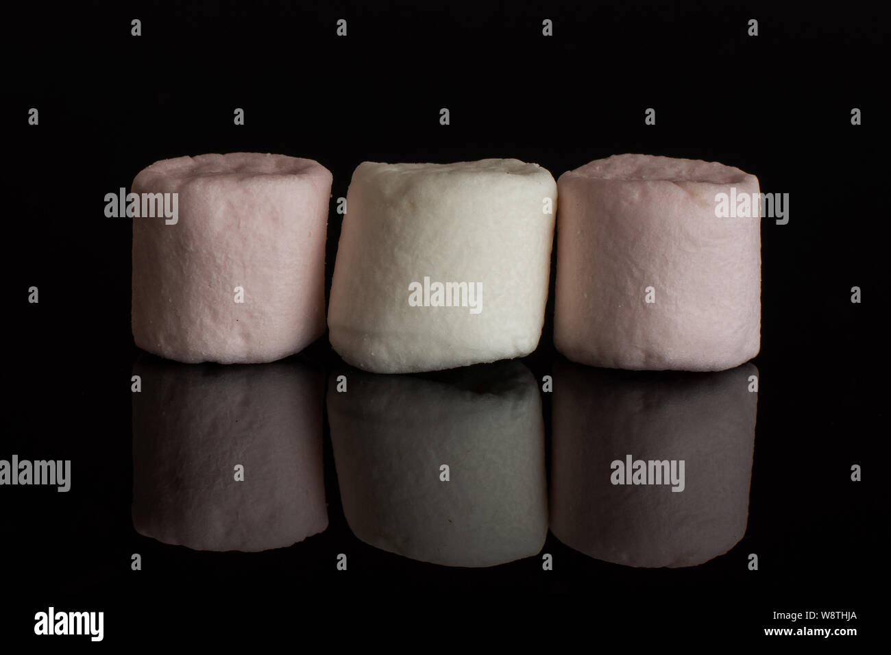 Group of three whole sweet fluffy marshmallow isolated on black glass ...